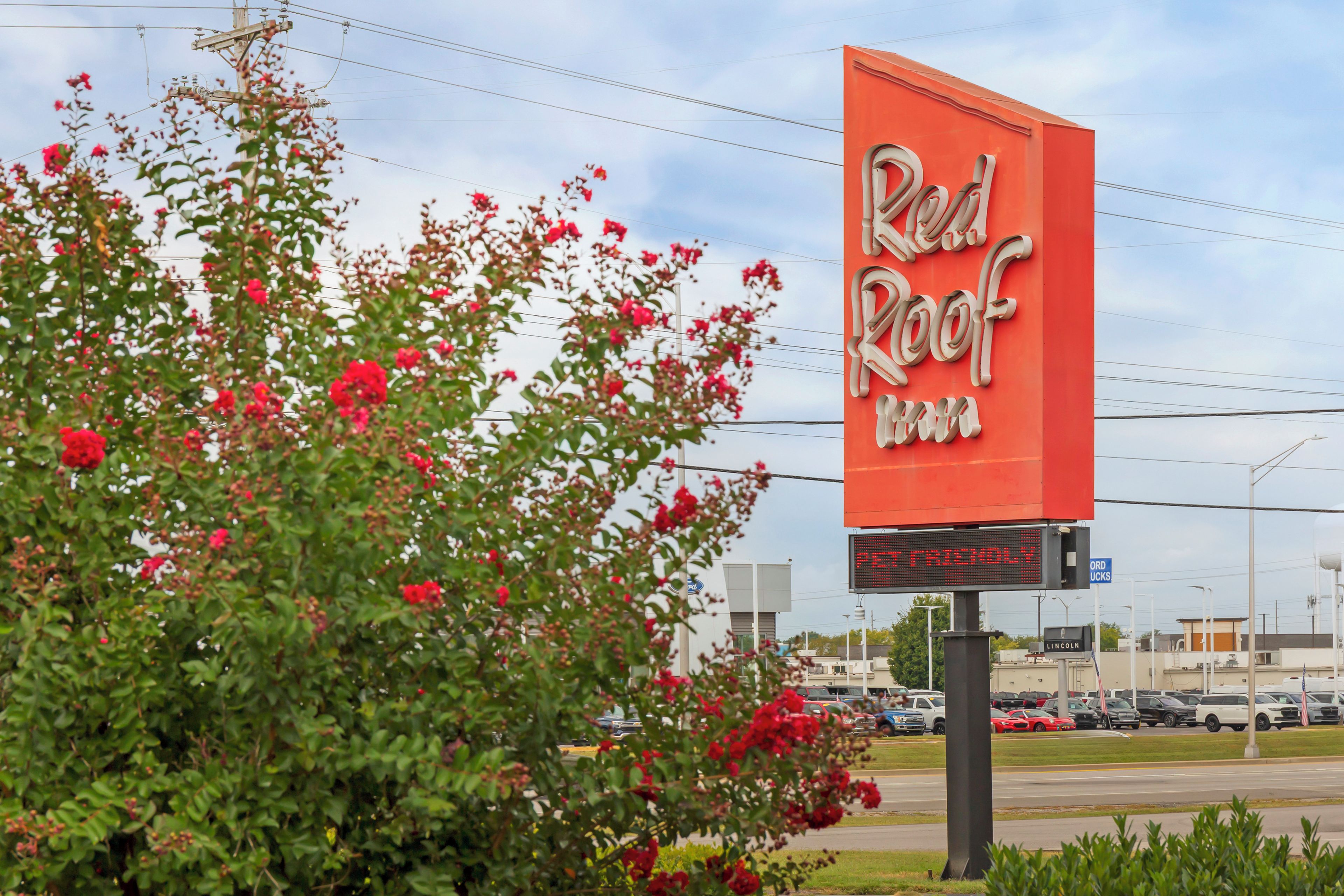 Um grande outdoor vermelho com a inscrição 'Red Roof Inn' e um painel digital abaixo.