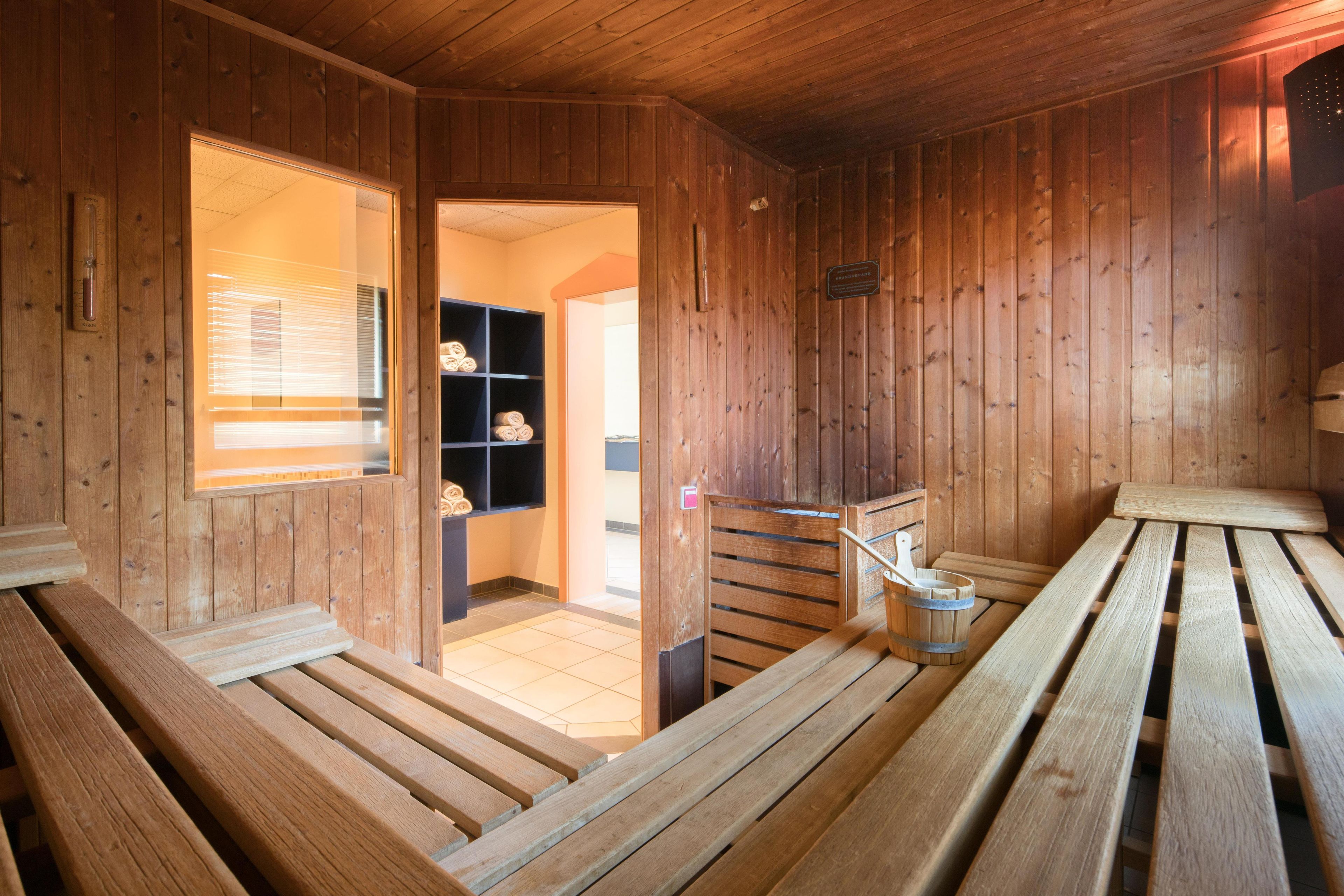 Uma sauna de madeira com bancos e um balde.