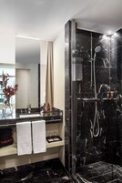 Uma casa de banho moderna com chuveiro de vidro, toucador com espelho e secador de cabelo no balcão.