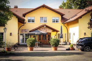 Um edifício amarelo com telhado ladrilhado, um restaurante e uma placa de hotel.