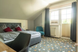 Quarto com uma cama, uma cadeira, um radiador e uma janela com cortinas.