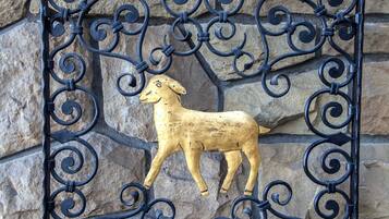 Arte de parede decorativa em metal com uma figura dourada de animal, fixada numa parede de pedra.