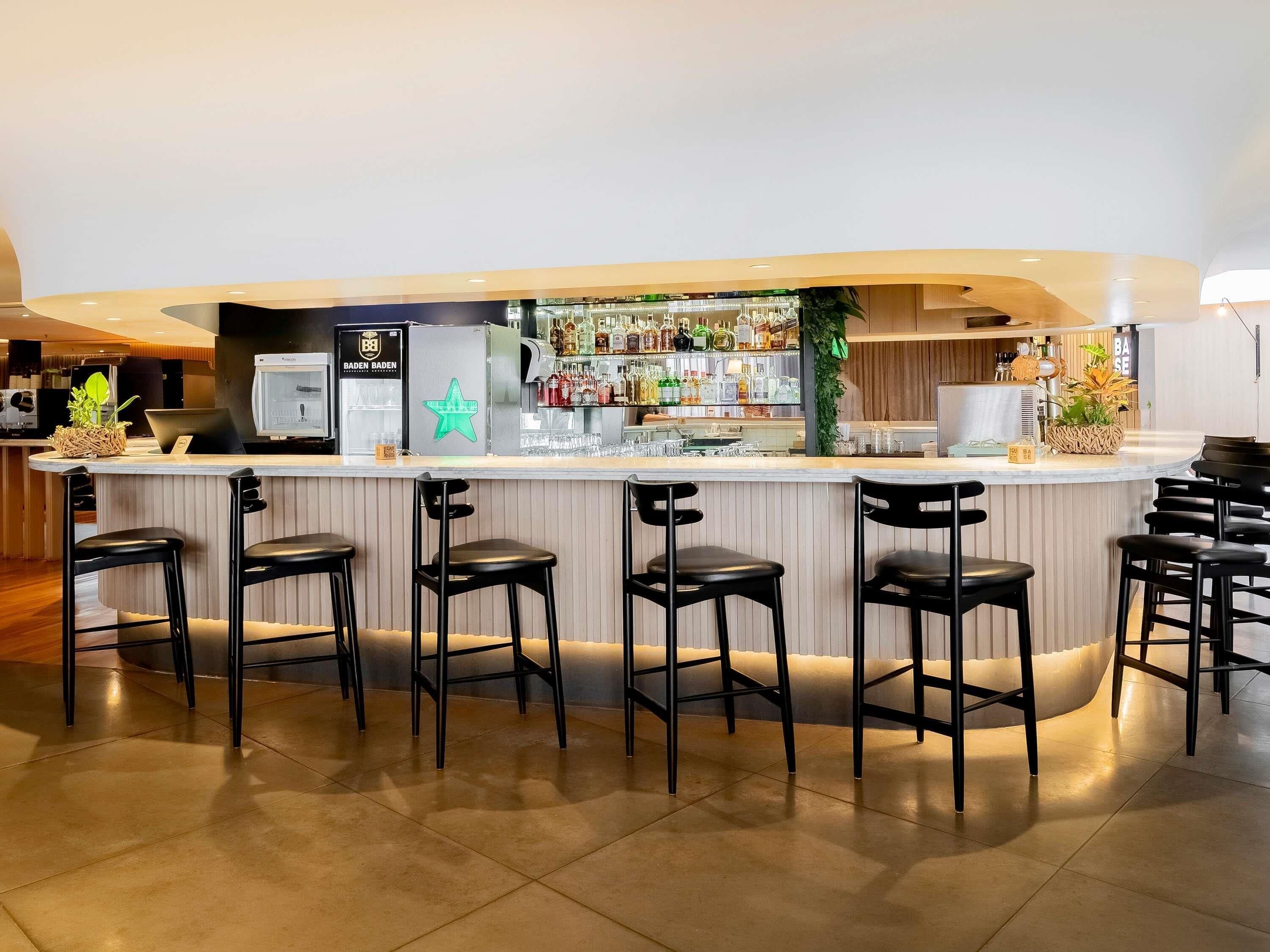 Uma área de bar com balcão, banquetes e geladeira.