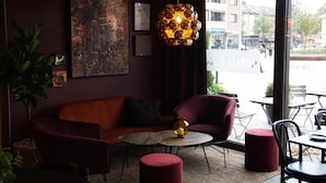 Um interior moderno com um sofá, poltronas, uma mesa redonda e uma luminária esférica original.