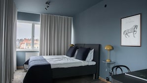Quarto com cama, janela com cortinas, luminária e quadro pendurado na parede.