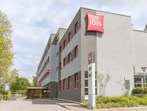 Um edifício moderno com uma placa grande da marca 'ibis', indicando que é um hotel.