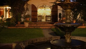 Uma fonte em um jardim com um edifício ao fundo.
