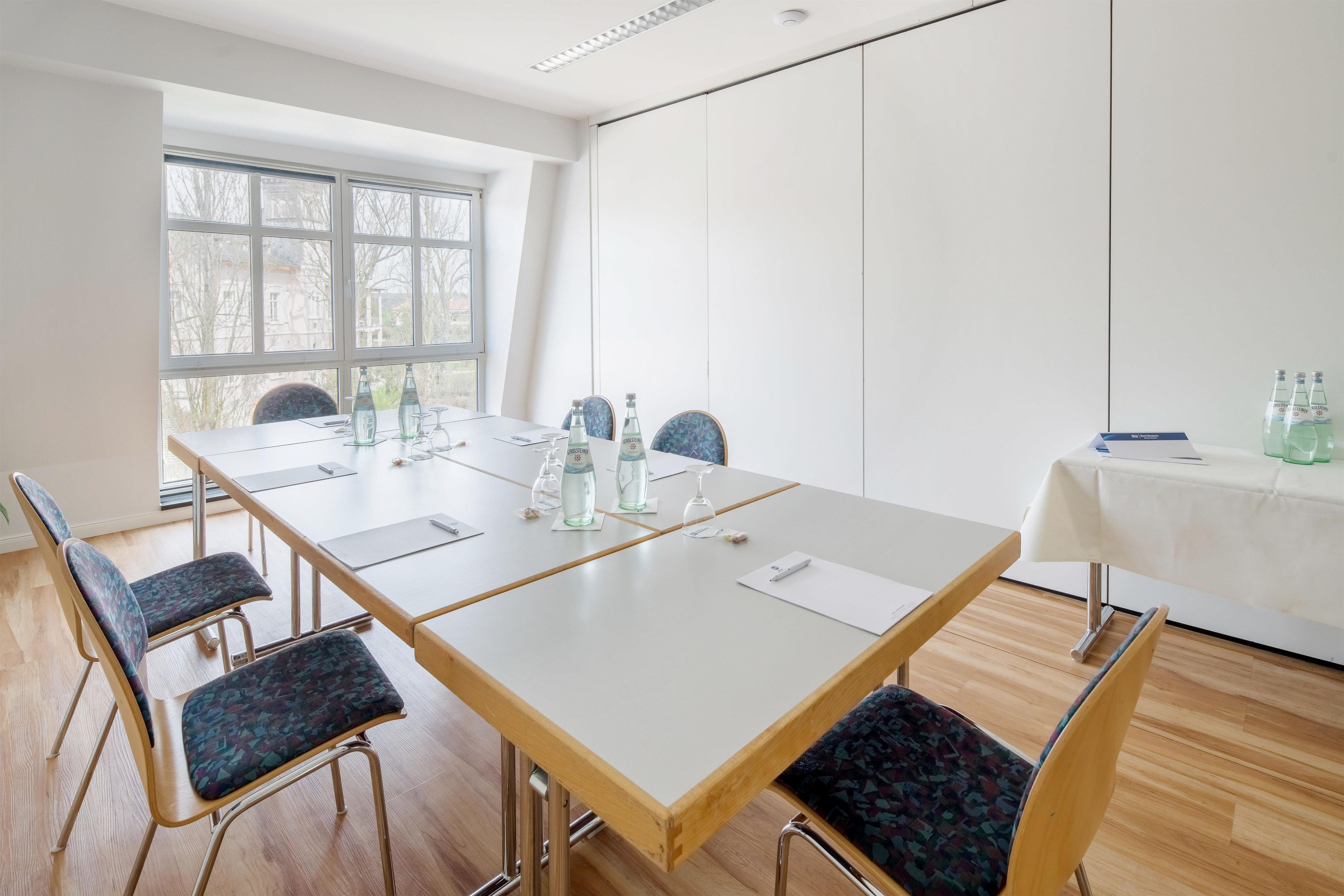 Uma sala de conferências com uma mesa comprida, cadeiras e um quadro branco.