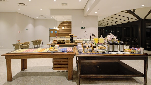 Disposição de buffet com diversos alimentos e área de refeições com cadeiras e mesas.