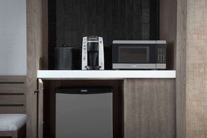 Cozinha equipada com cafeteira, micro-ondas e máquina de lavar loiça.