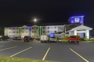 Um Sleep Inn com vários espaços de estacionamento e fachada do edifício bem iluminada.