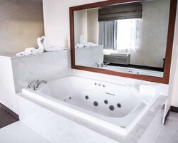 Um banheiro moderno com uma banheira grande, um espelho e uma janela com cortinas.