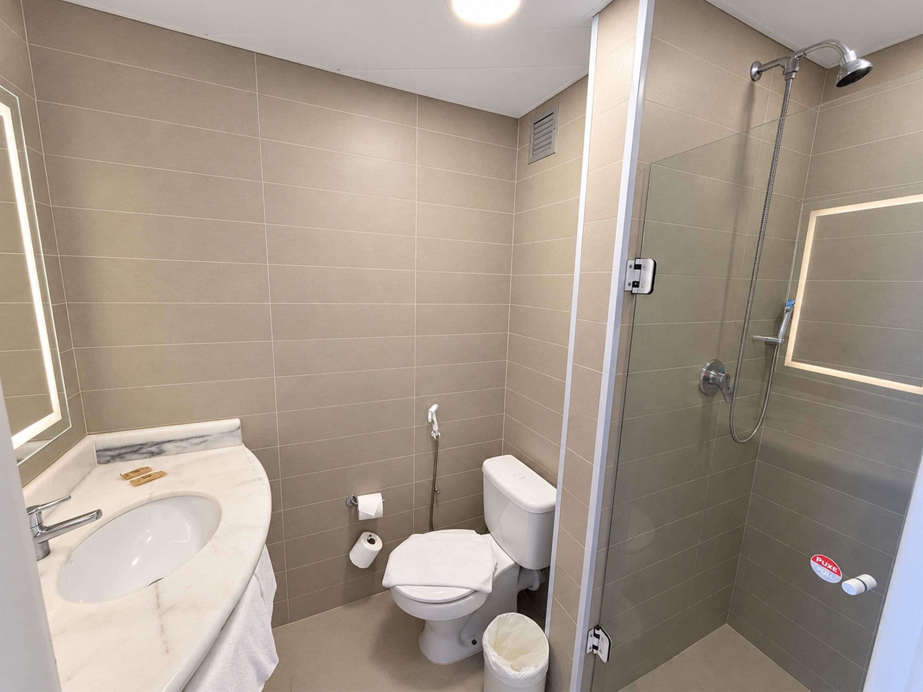Uma casa de banho moderna com lavatório, sanita e chuveiro.