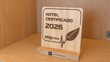 Placa de madeira com os textos 'HOTEL CERTIFICADO 2026' e 'esgpulse', fixada em uma base de madeira.