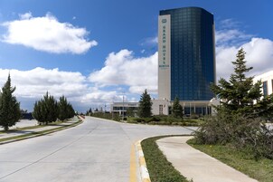 Um hotel moderno com fachada de vidro destacada, um gramado bem cuidado e céu claro.
