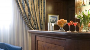 Uma área de bar com balcão de madeira, uma poltrona azul e um vaso com flores.