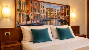 Quarto de hotel com uma grande pintura de uma cena de canal, duas mesas de cabeceira com luminárias e uma cama com almofadas verde-água.