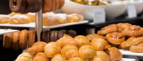 Buffet com diversos doces, incluindo croissants e donuts.