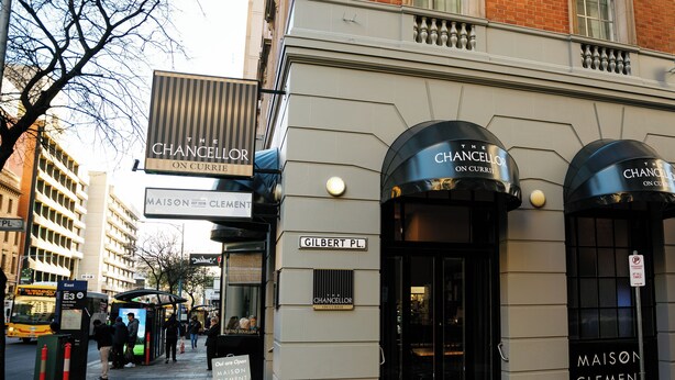 Um edifício com placas indicando 'The Chancellor on Currie' e 'Maison Clement'.