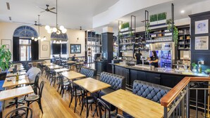 Um restaurante com várias mesas e cabines, um bar e cozinha ao fundo.