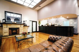 Uma sala de estar ampla com lareira, um sofá de couro e uma cozinha moderna ao fundo.