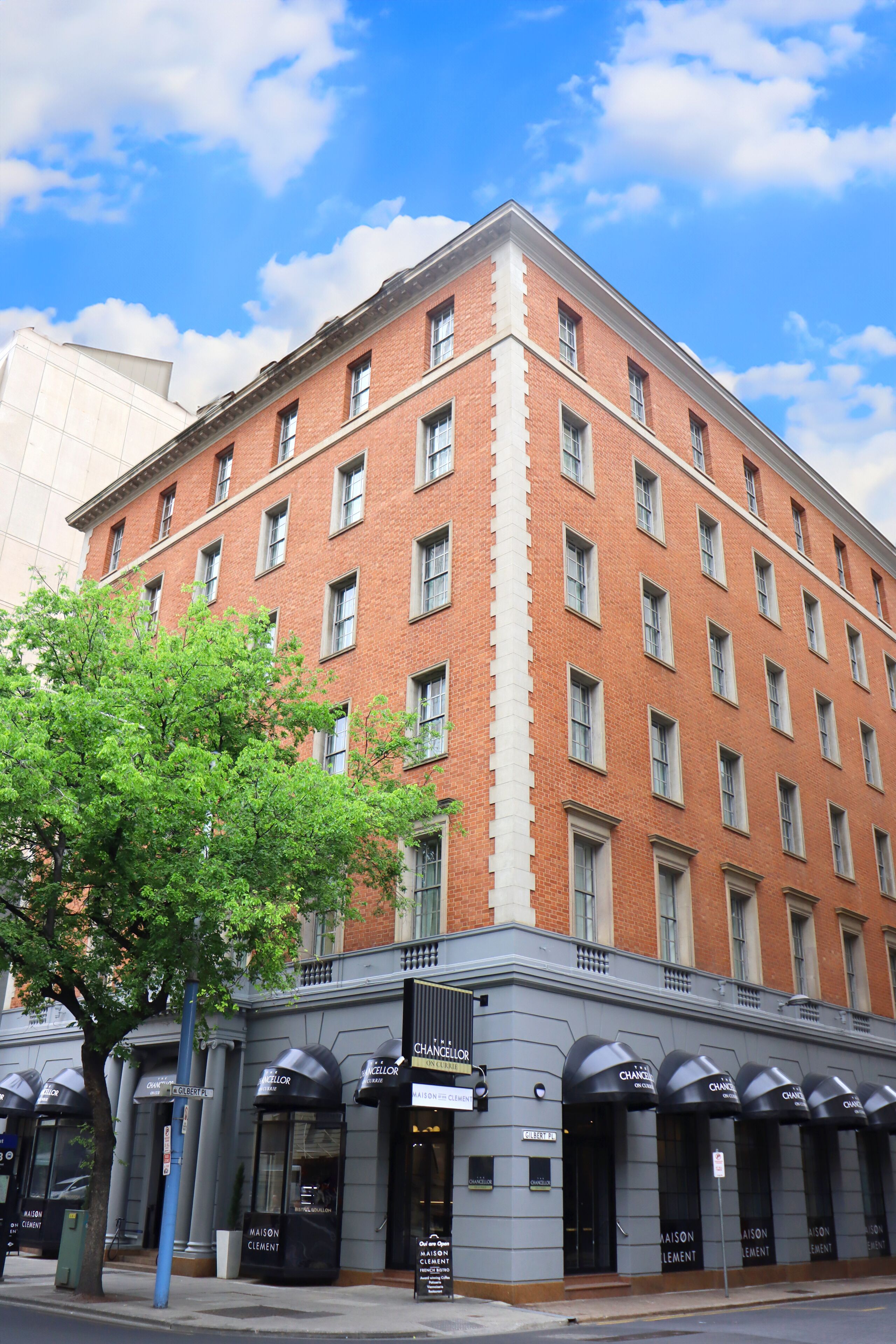 Um edifício de tijolos vermelhos com várias janelas e um toldo preto com a marca 'Chanel'.