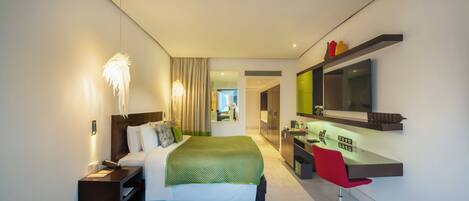 Quarto de hotel moderno com cama, escrivaninha e vista para a cozinha.