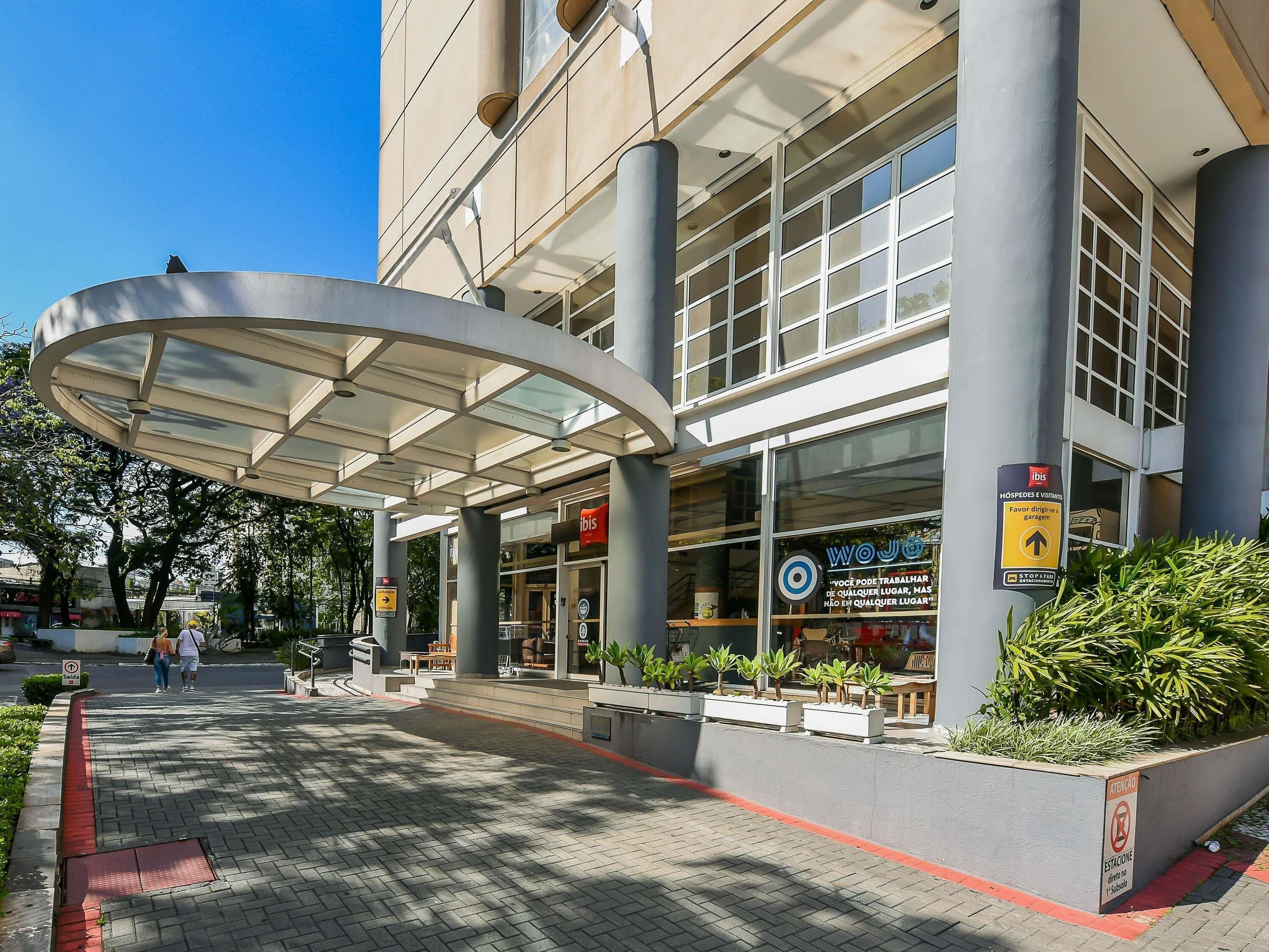 Um edifício moderno com entrada coberta, área de estar ao ar livre e uma placa indicando um hotel.