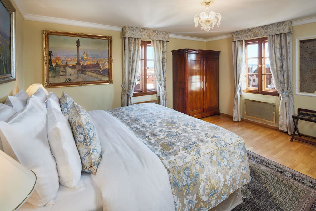 Quarto com uma cama, um guarda-roupa de madeira, um quadro e vista para a cidade através da janela.