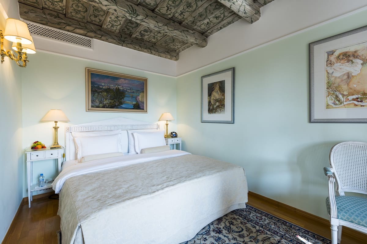 Quarto bem arrumado com uma cama grande, duas mesas de cabeceira com abajures e uma cadeira.
