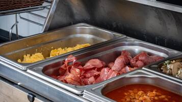 Buffet com diversos alimentos, incluindo ovos mexidos, bacon, linguiça e feijão com molho.