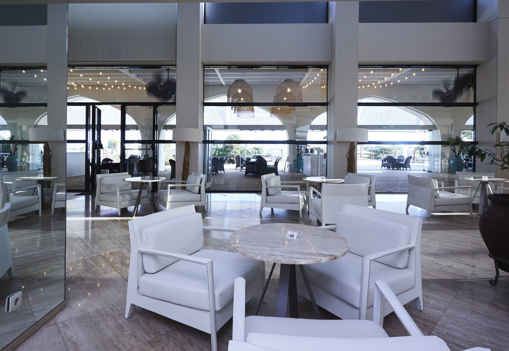 Interior moderno com móveis brancos, uma mesa de mármore e amplas janelas com vista.