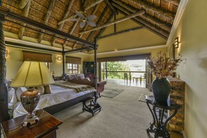 Um quarto espaçoso com uma cama grande, um ventilador de teto e vista para o exterior.