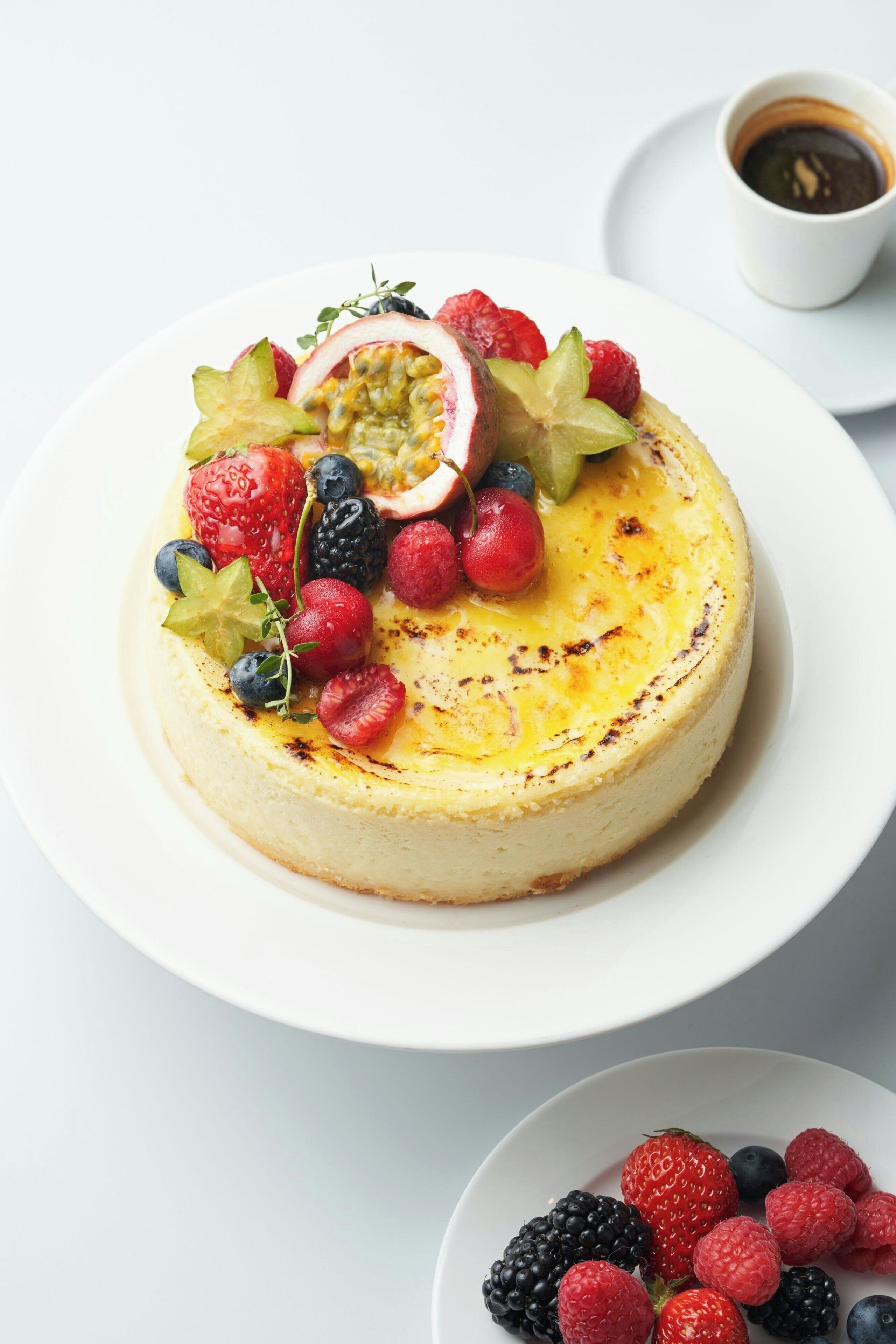 Um cheesecake coberto com diversas frutas sobre um prato branco.