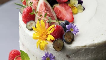 Um bolo com várias frutas e flores no topo.