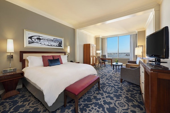 Quarto de hotel com cama grande, escrivaninha, televisão e vista para a cidade.