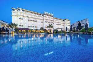 Hotel com uma piscina grande, área de estar externa e vista clara da fachada do edifício.
