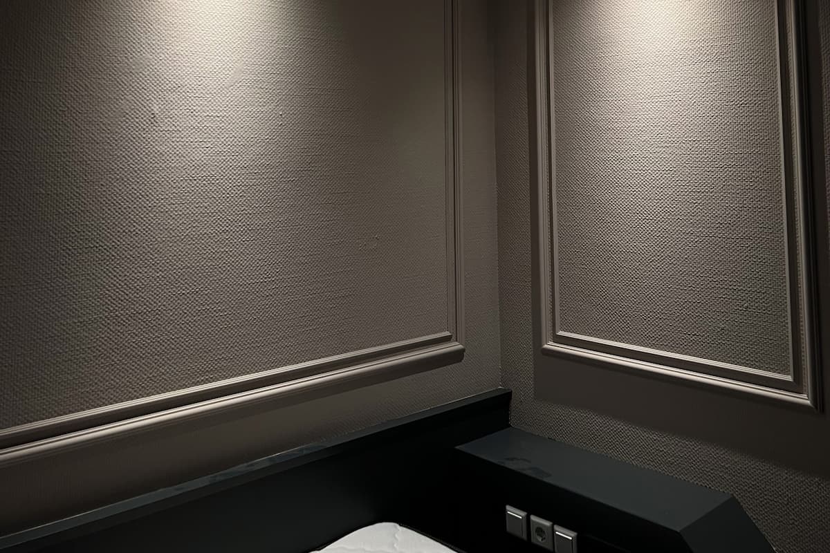 Quarto com uma cama grande, mesa de cabeceira e luminária fixada na parede.