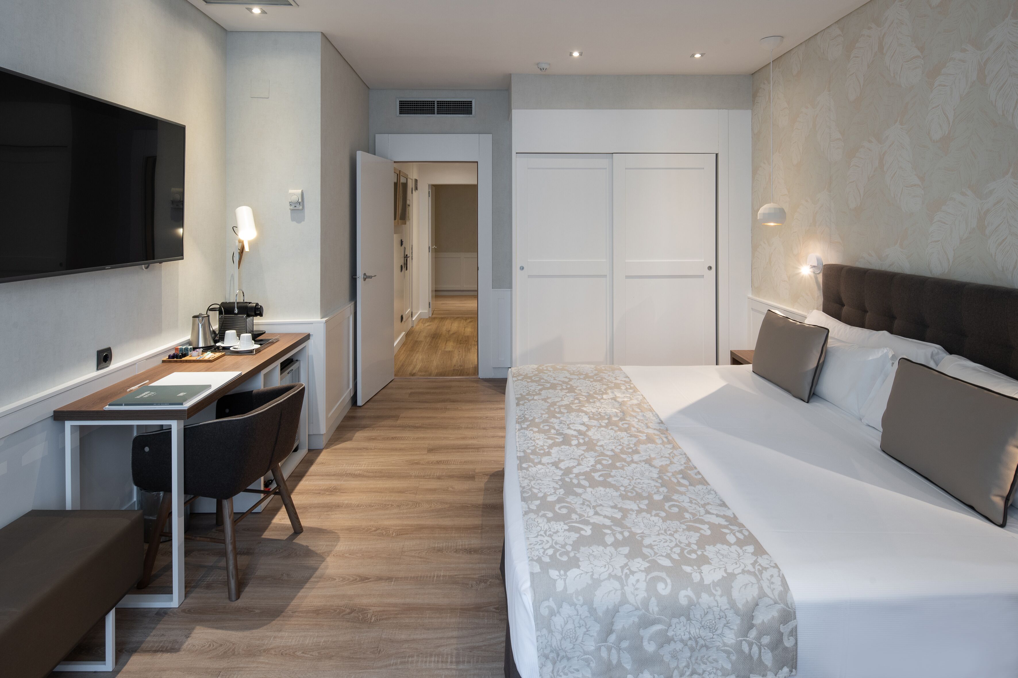 Quarto de hotel moderno com cama, escrivaninha e televisão.