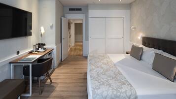 Quarto de hotel moderno com cama, escrivaninha e televisão.