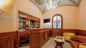Uma área de bar com armários de madeira, uma televisão e um candelabro.