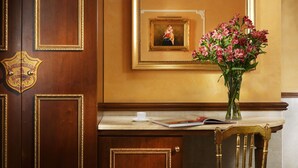 Uma porta de madeira com um brasão, um quadro emoldurado, um vaso com flores e uma revista sobre uma bancada de mármore.