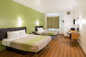 Quarto de hotel com duas camas, uma escrivaninha, uma cadeira e uma janela com cortinas.