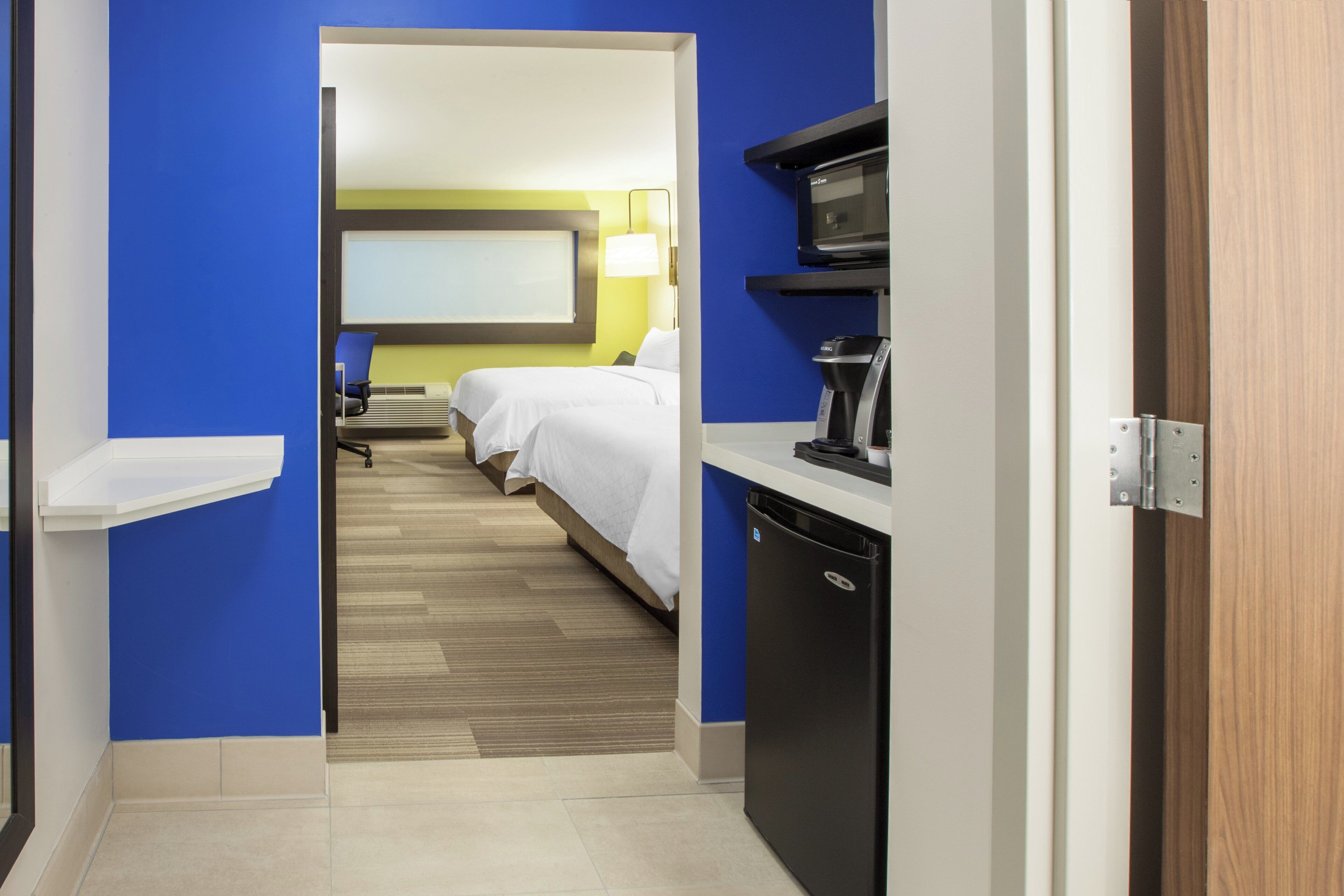 Quarto de hotel com cama, escrivaninha e máquina de café.