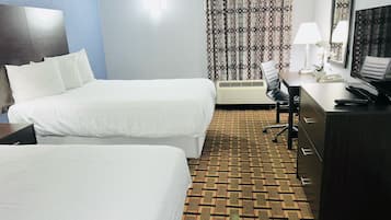 Quarto de hotel com duas camas, uma escrivaninha, uma cadeira, televisão e janela com cortinas estampadas.