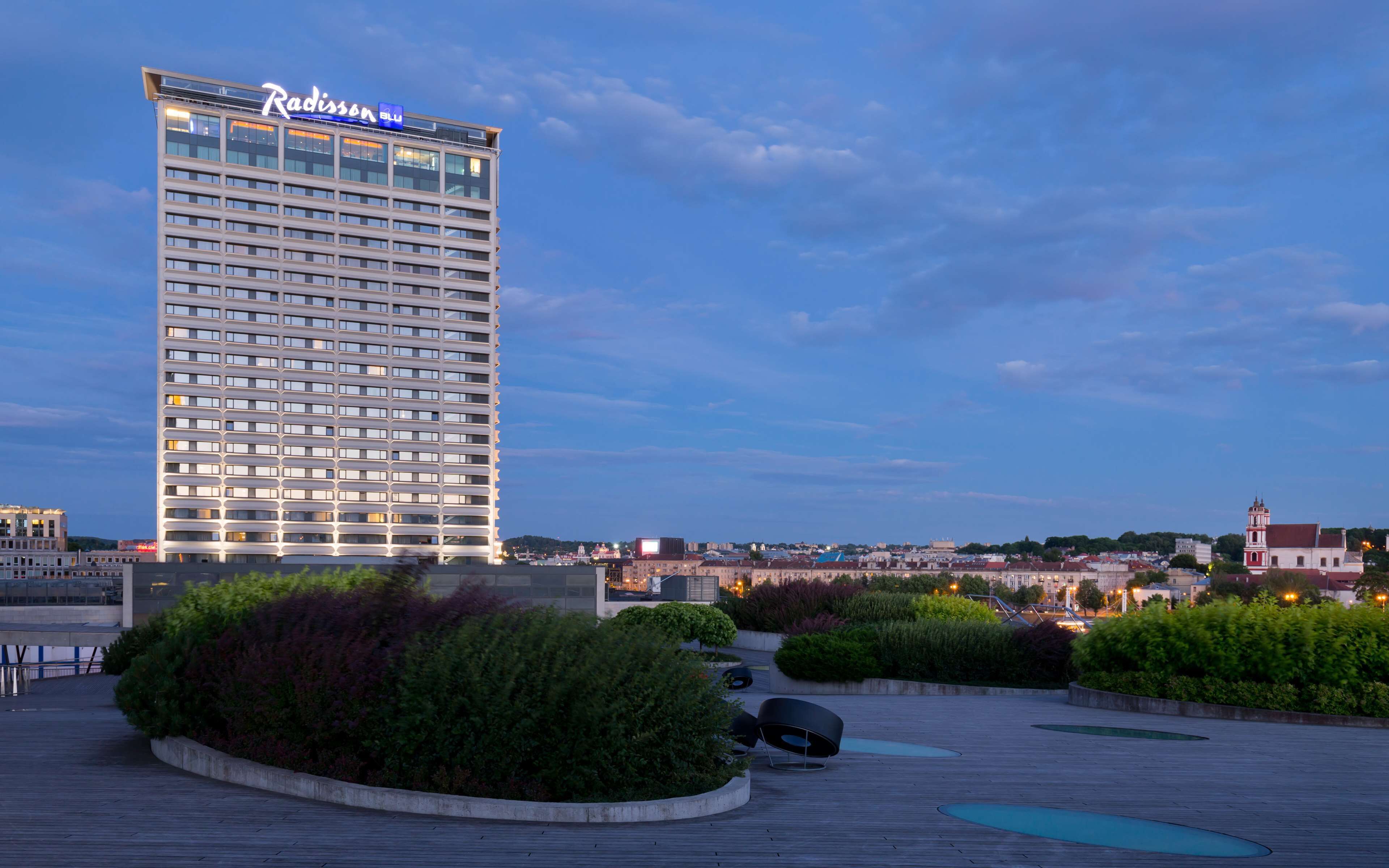Um hotel moderno e imponente, com um design contemporâneo e o nome 'Radisson' em destaque no topo.
