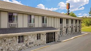Um motel com fachada de pedra, vários aparelhos de ar condicionado e céu claro.