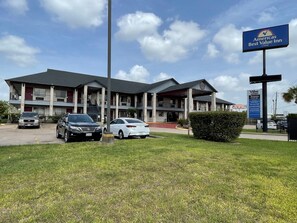 Um motel de vários andares com entrada central e estacionamento.
