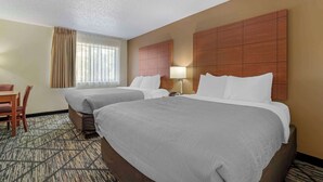 Quarto de hotel com duas camas, uma escrivaninha e uma cadeira.