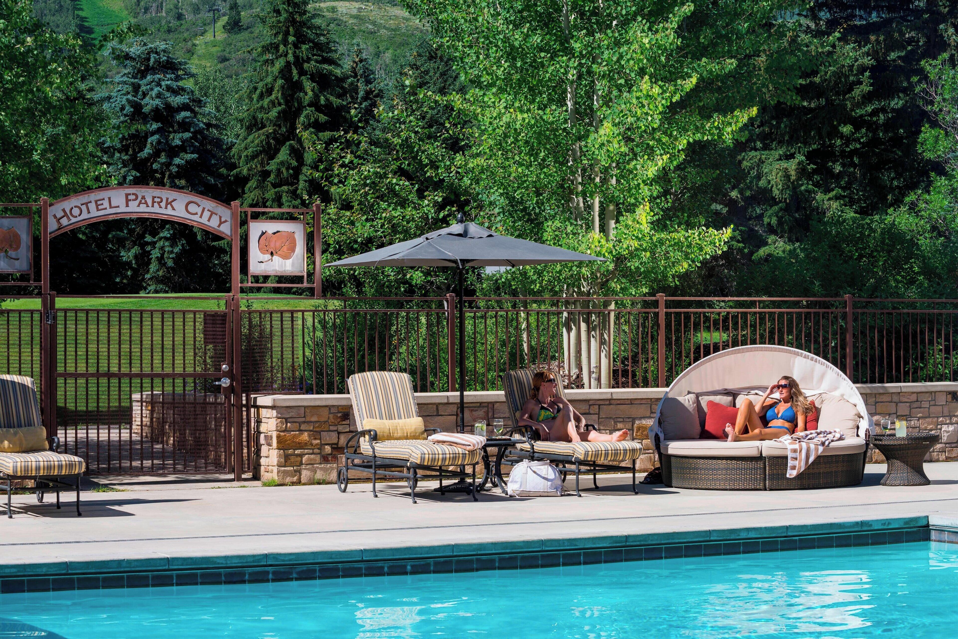 Uma área junto à piscina com espreguiçadeiras e uma placa com a inscrição 'Hotel Park City'.